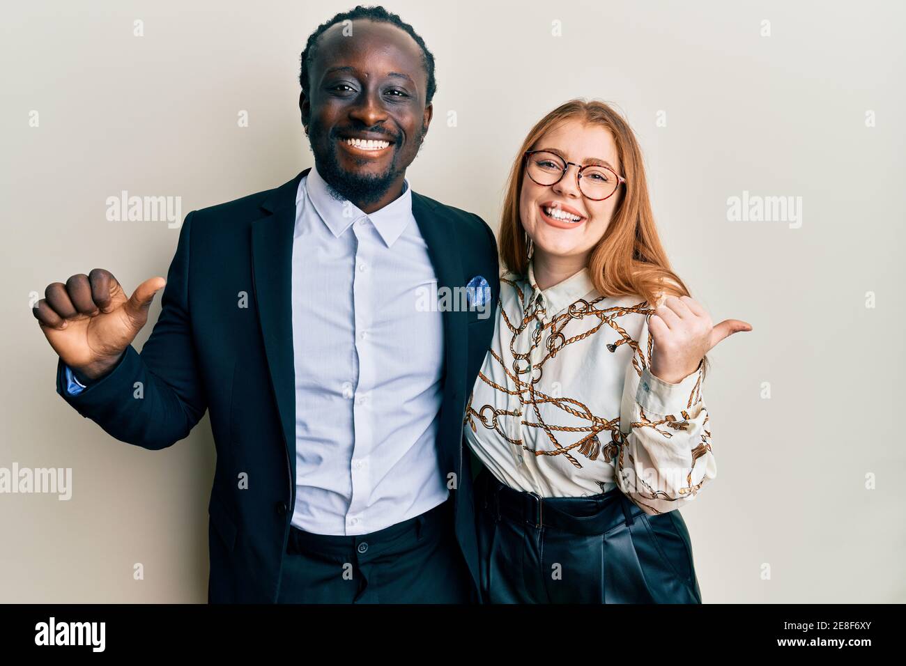 Young Interracial Couple Wearing Business And Elegant Clothes Pointing