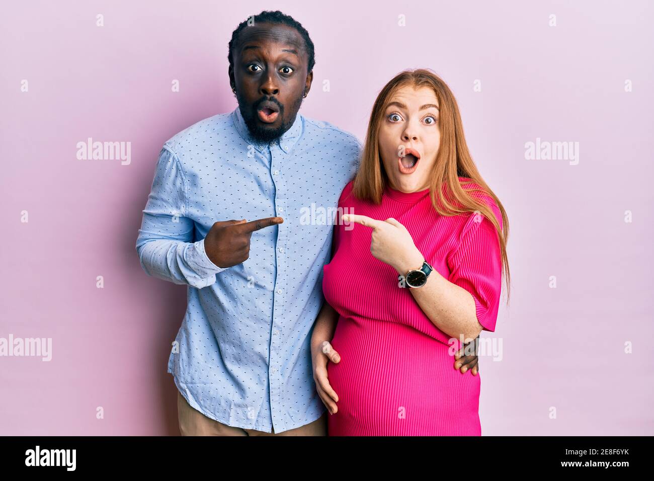 Young interracial couple expecting a baby, touching pregnant belly ...