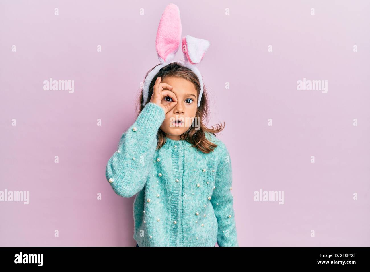 Little beautiful girl wearing cute easter bunny ears doing ok gesture ...