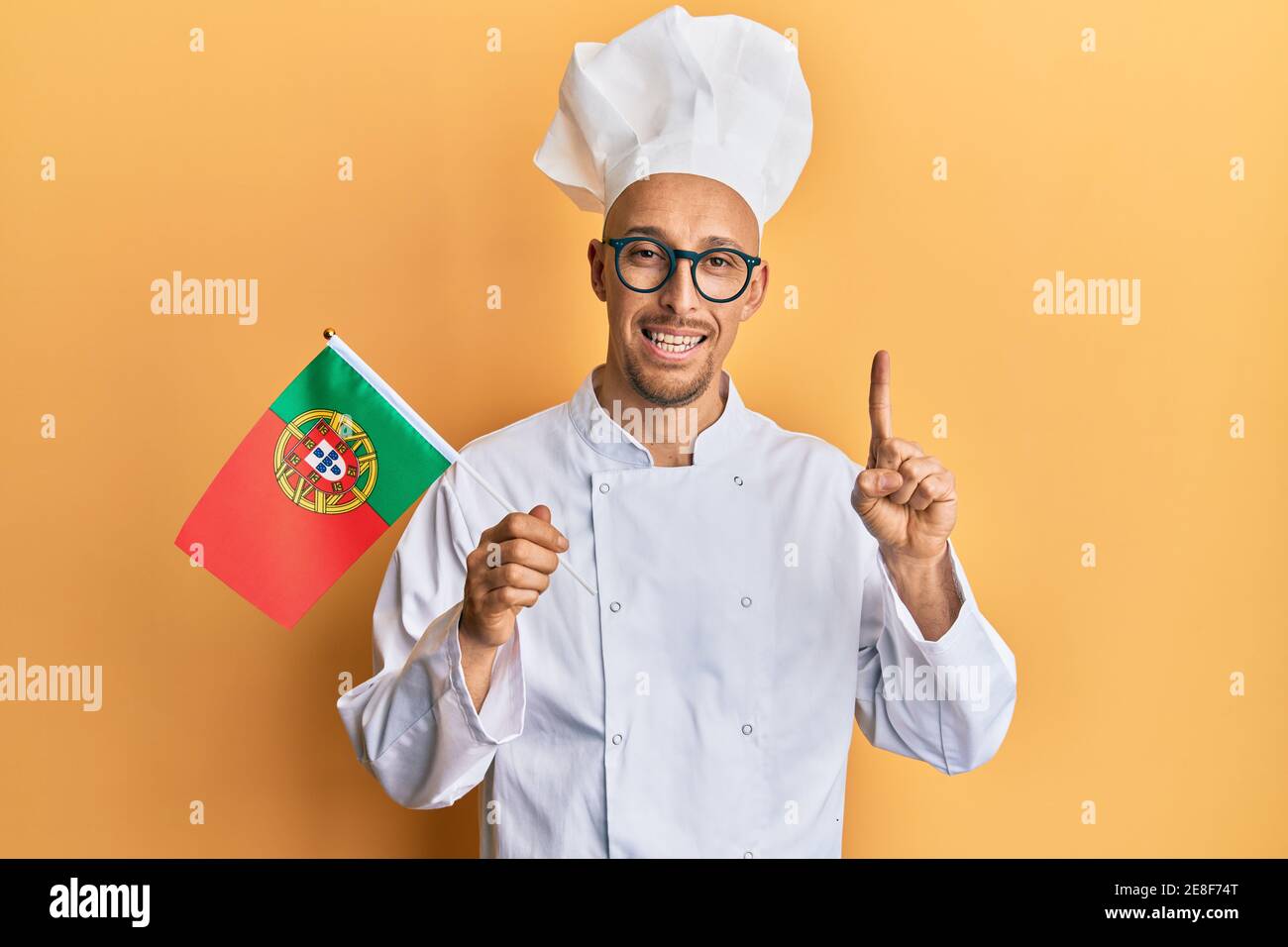 Bald man with beard wearing professional cook apron holding portugal ...