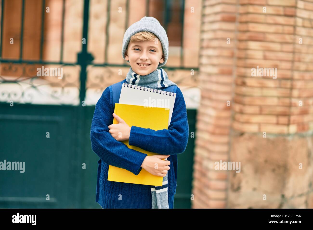 Adorable blond student kid smiling happy holding book at the school ...