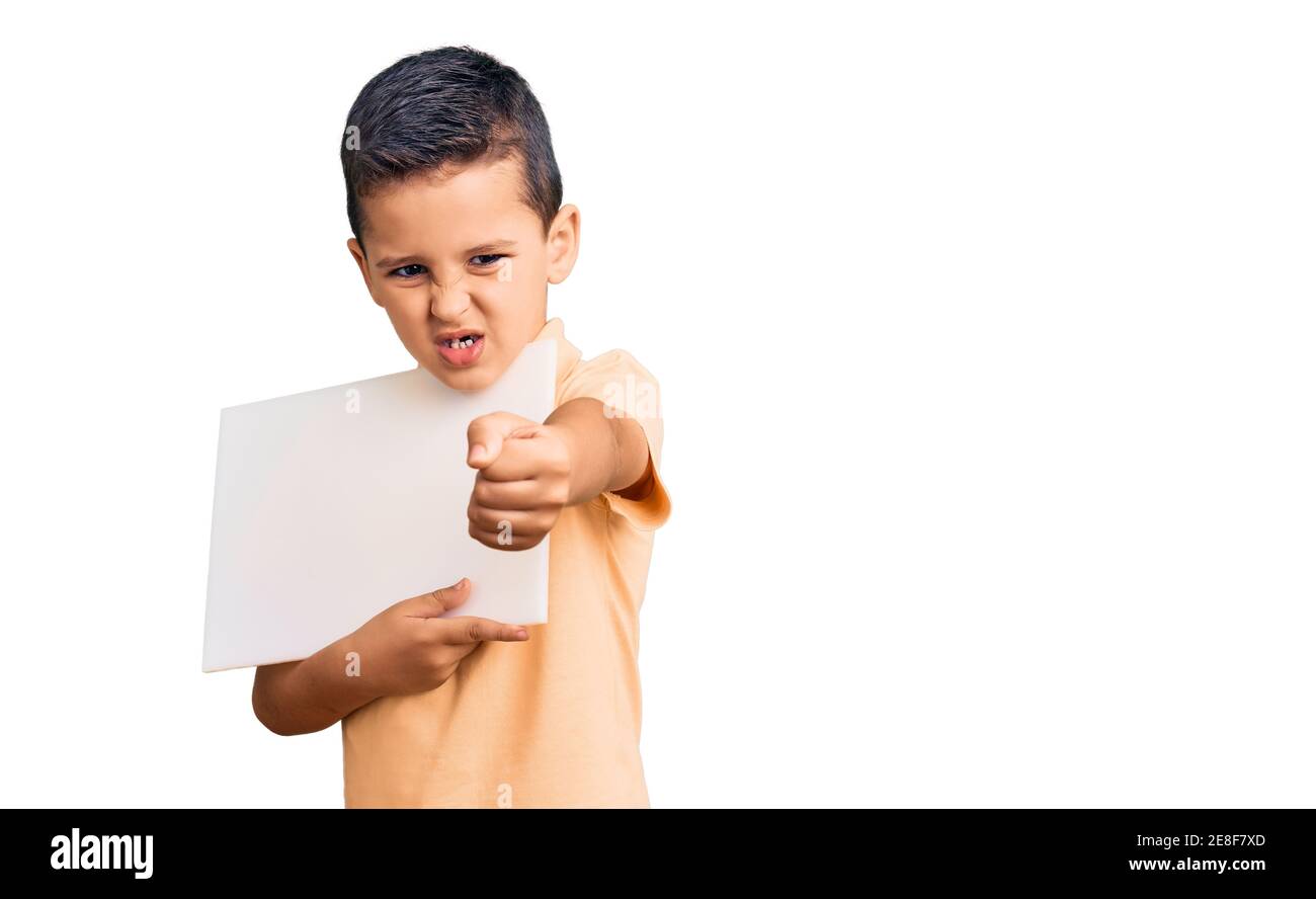 Little cute boy kid holding cardboard banner with blank space annoyed ...
