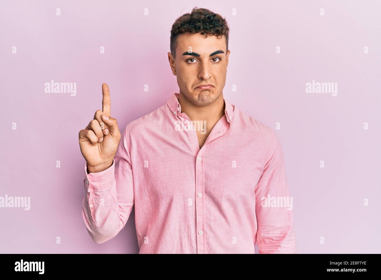 Hispanic young man pointing up with fingers depressed and worry for ...