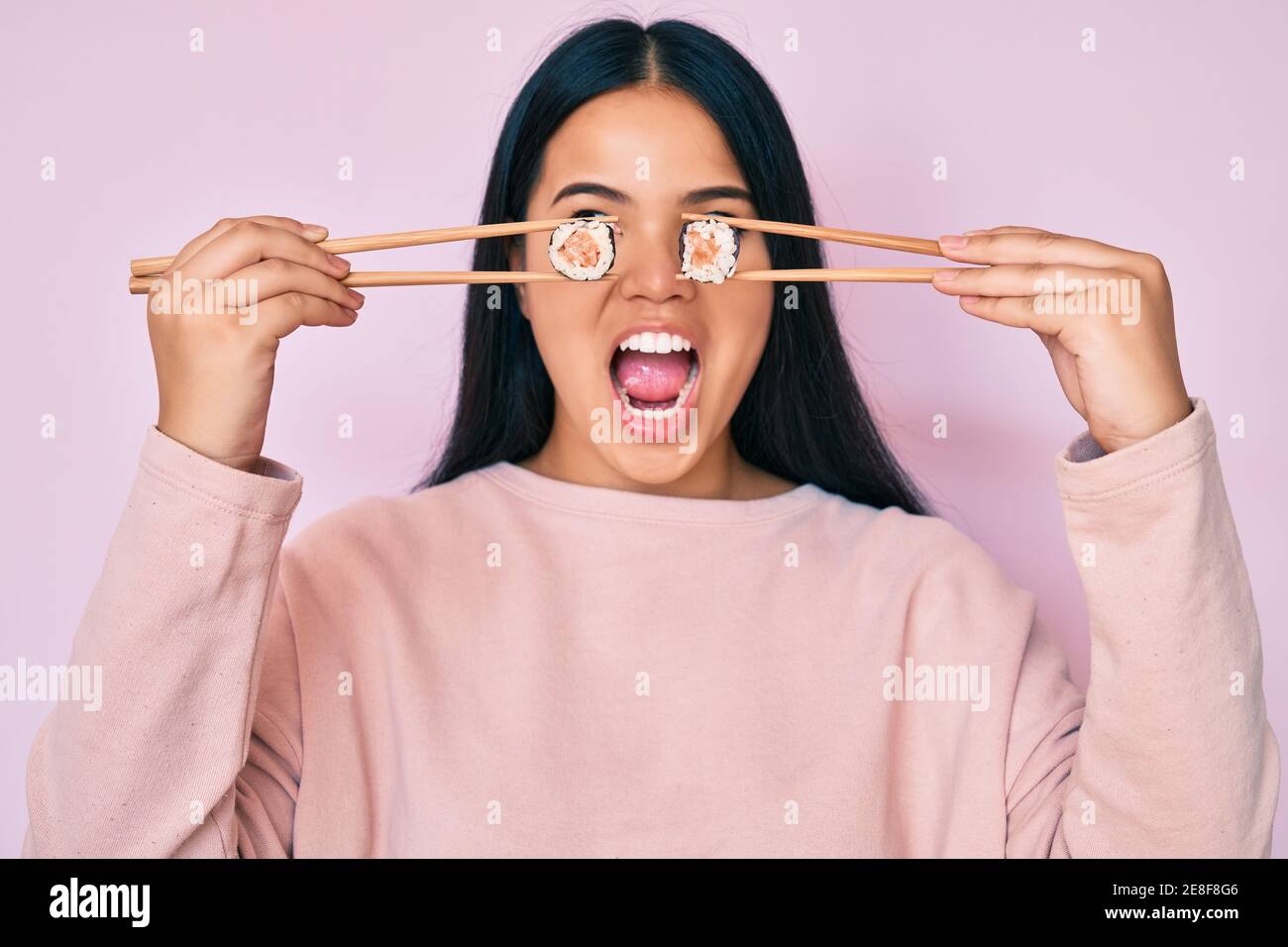 Young beautiful asian girl puting sushi on eyes using chopsticks angry ...
