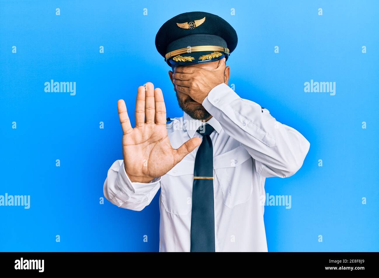 Handsome man with beard wearing airplane pilot uniform covering eyes ...