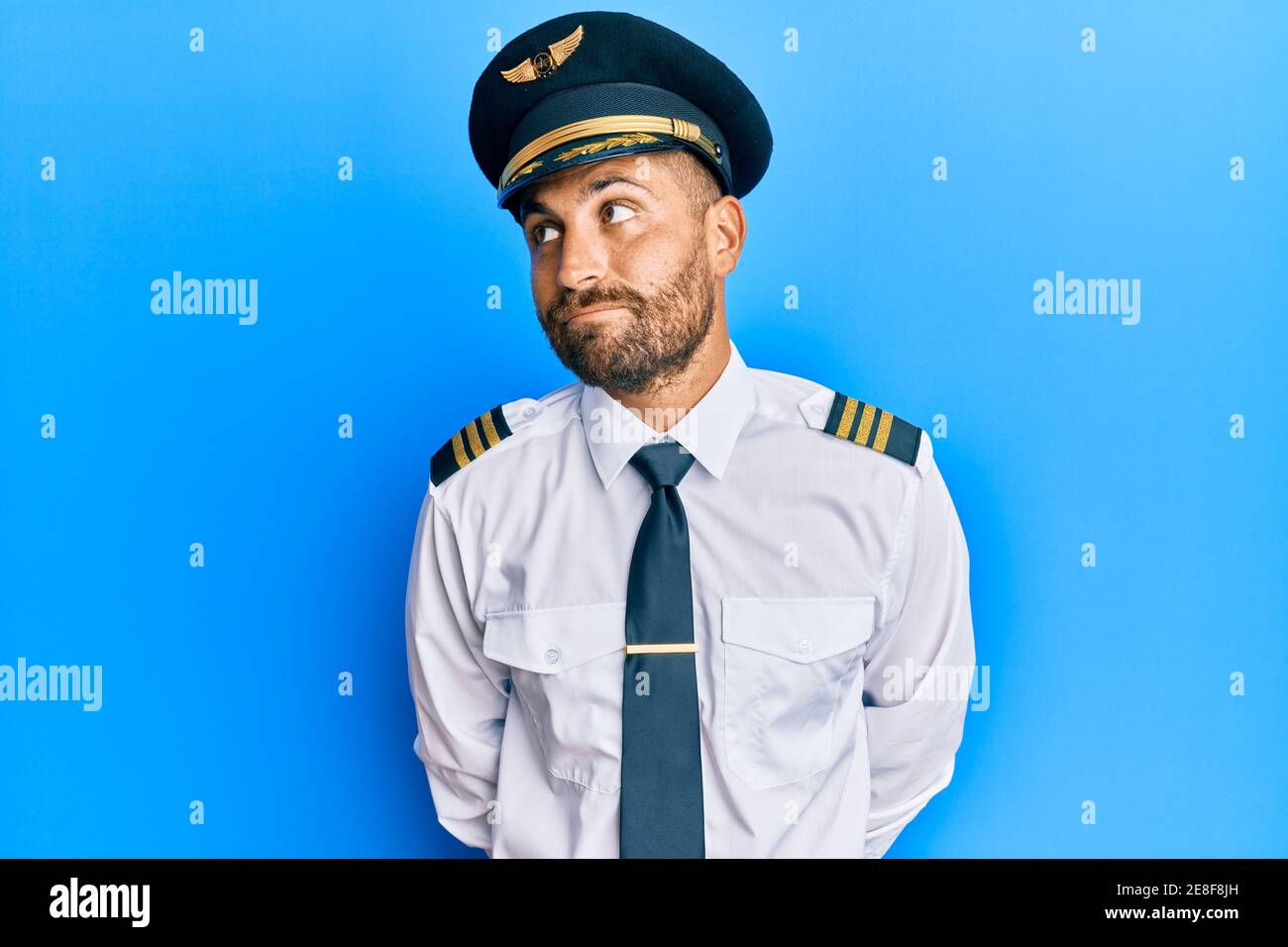 Handsome man with beard wearing airplane pilot uniform smiling looking ...