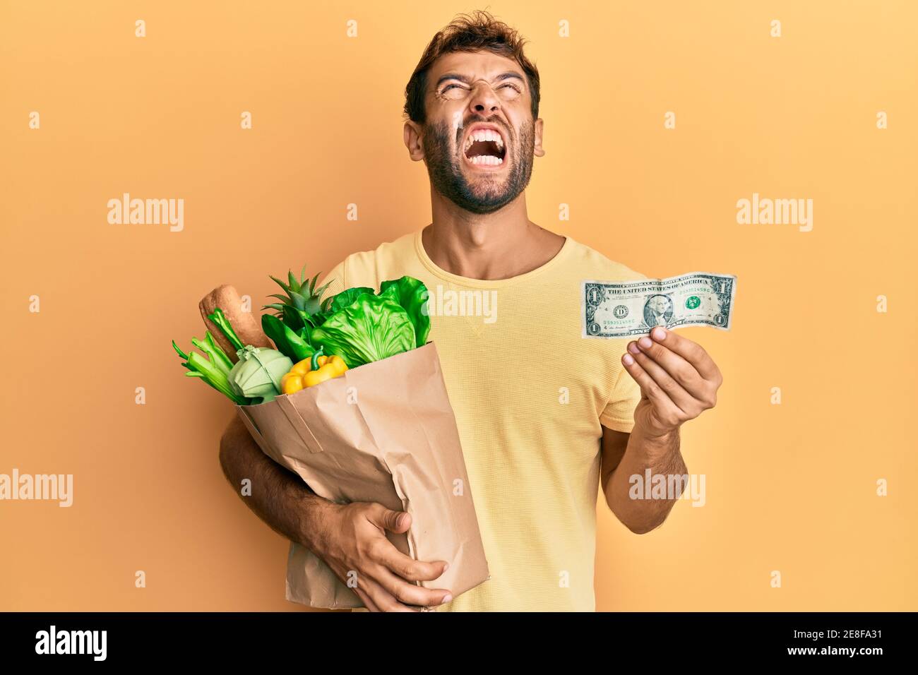 Handsome man with beard holding groceries and 1 american dollar ...