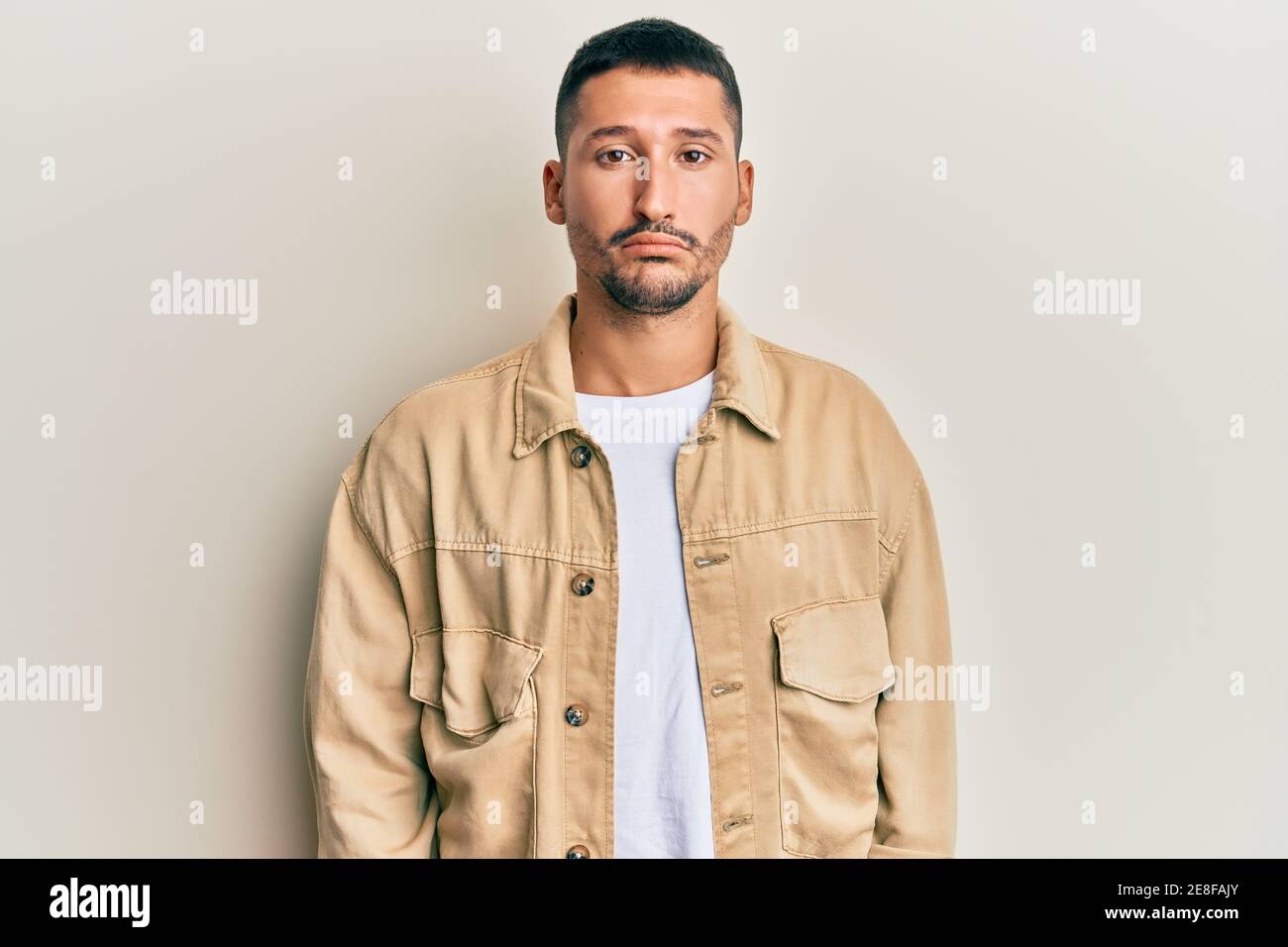 Handsome man with tattoos wearing casual brown denim jacket depressed ...
