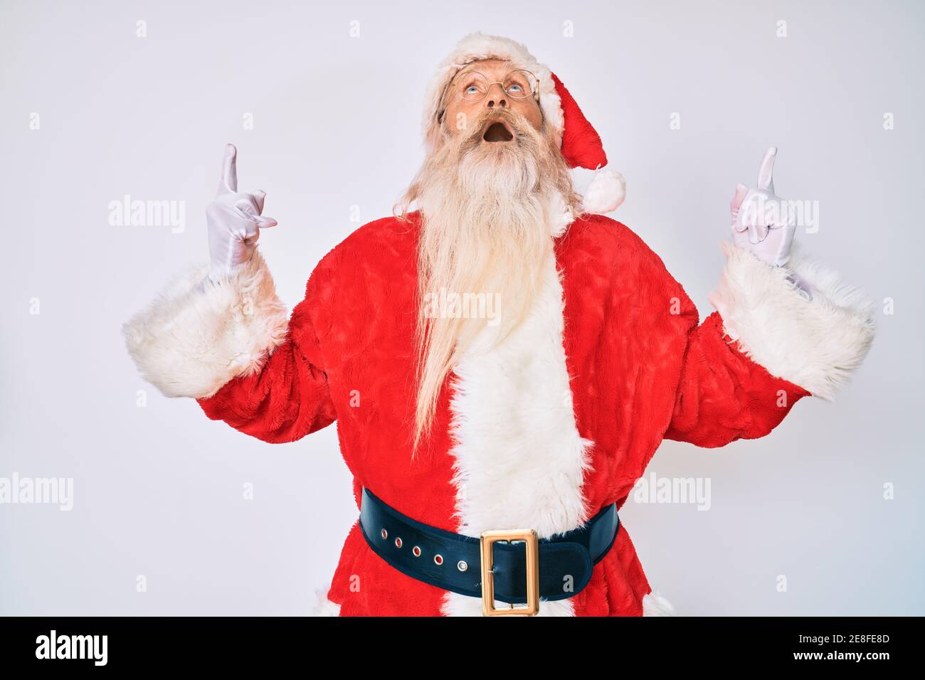 Old senior man with grey hair and long beard wearing santa claus ...