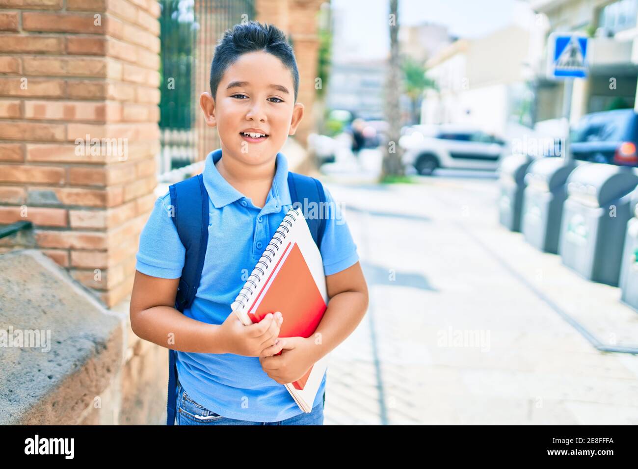 Adorable student boy smiling happy holding book at street of city Stock ...