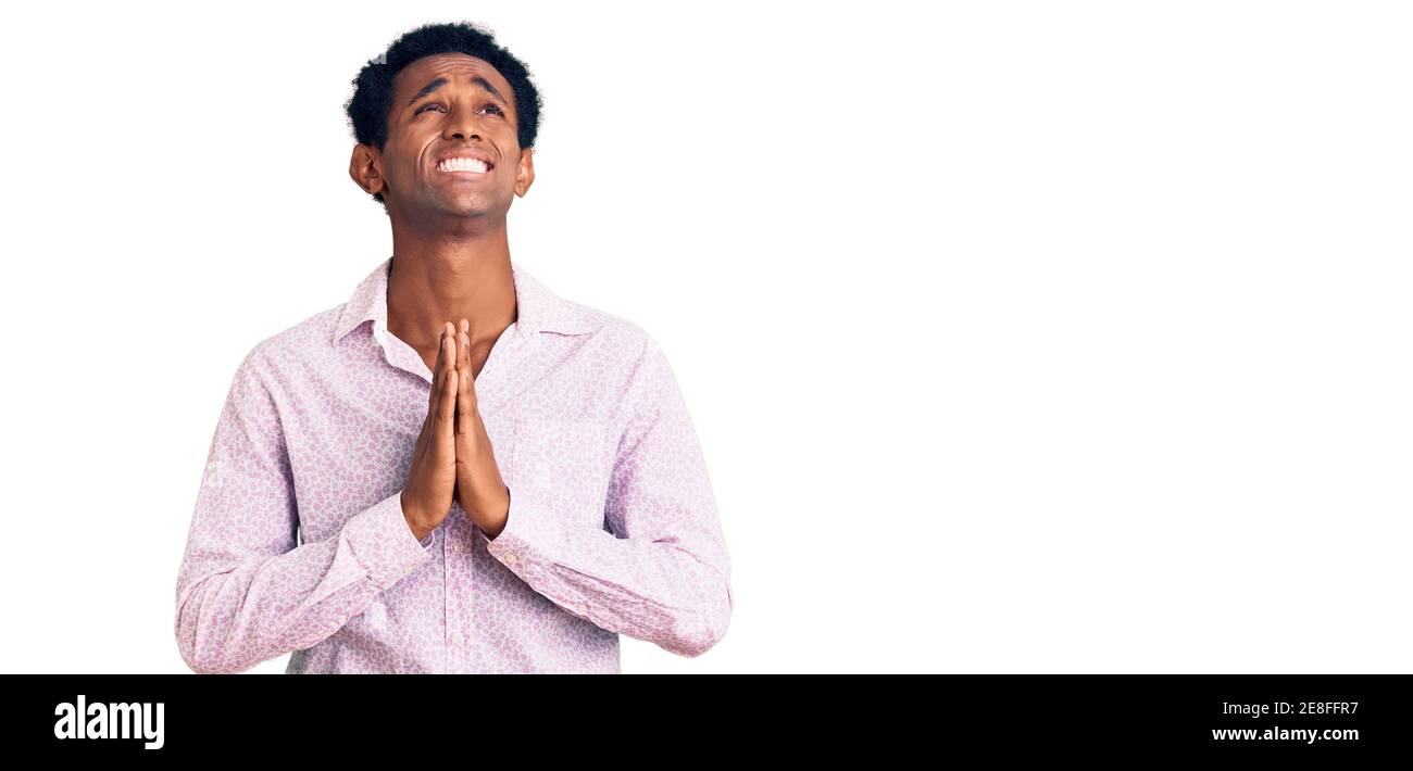 African handsome man wearing casual pink shirt begging and praying with ...