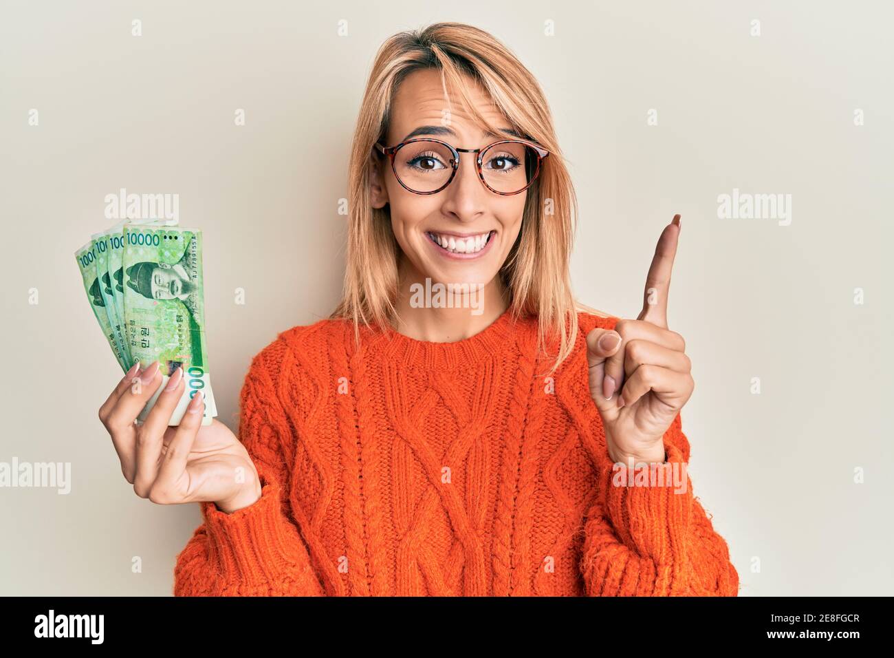 Beautiful blonde woman holding 10000 south korean won banknotes smiling ...