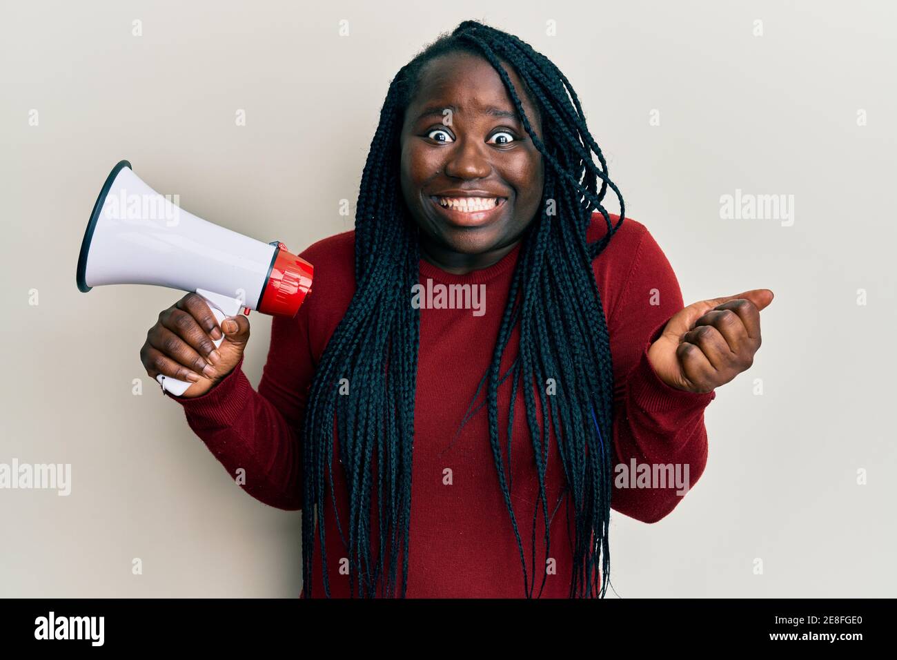 Young black woman with braids shouting through megaphone screaming ...