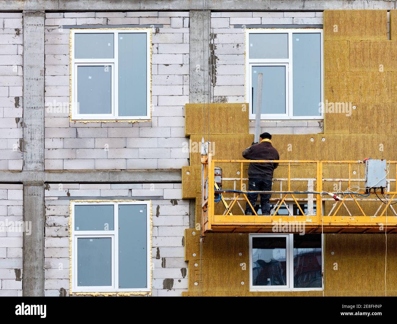 The builder stands on a suspended cradle and insulates the facade of ...