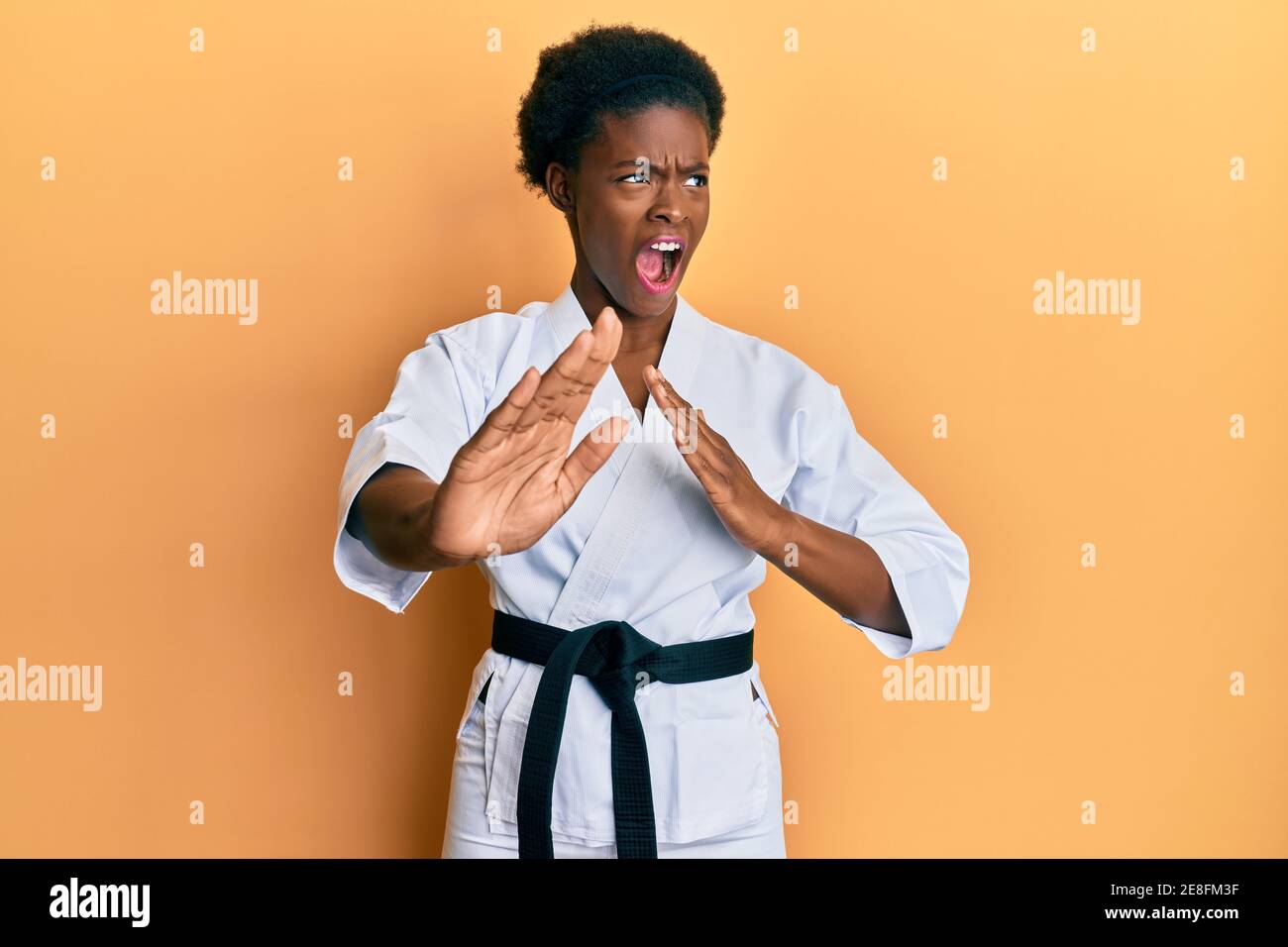 Young african american girl wearing karate kimono and black belt angry ...
