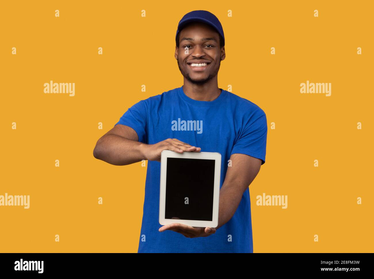 Black delivery man holding tablet with blank screen for mockup Stock ...