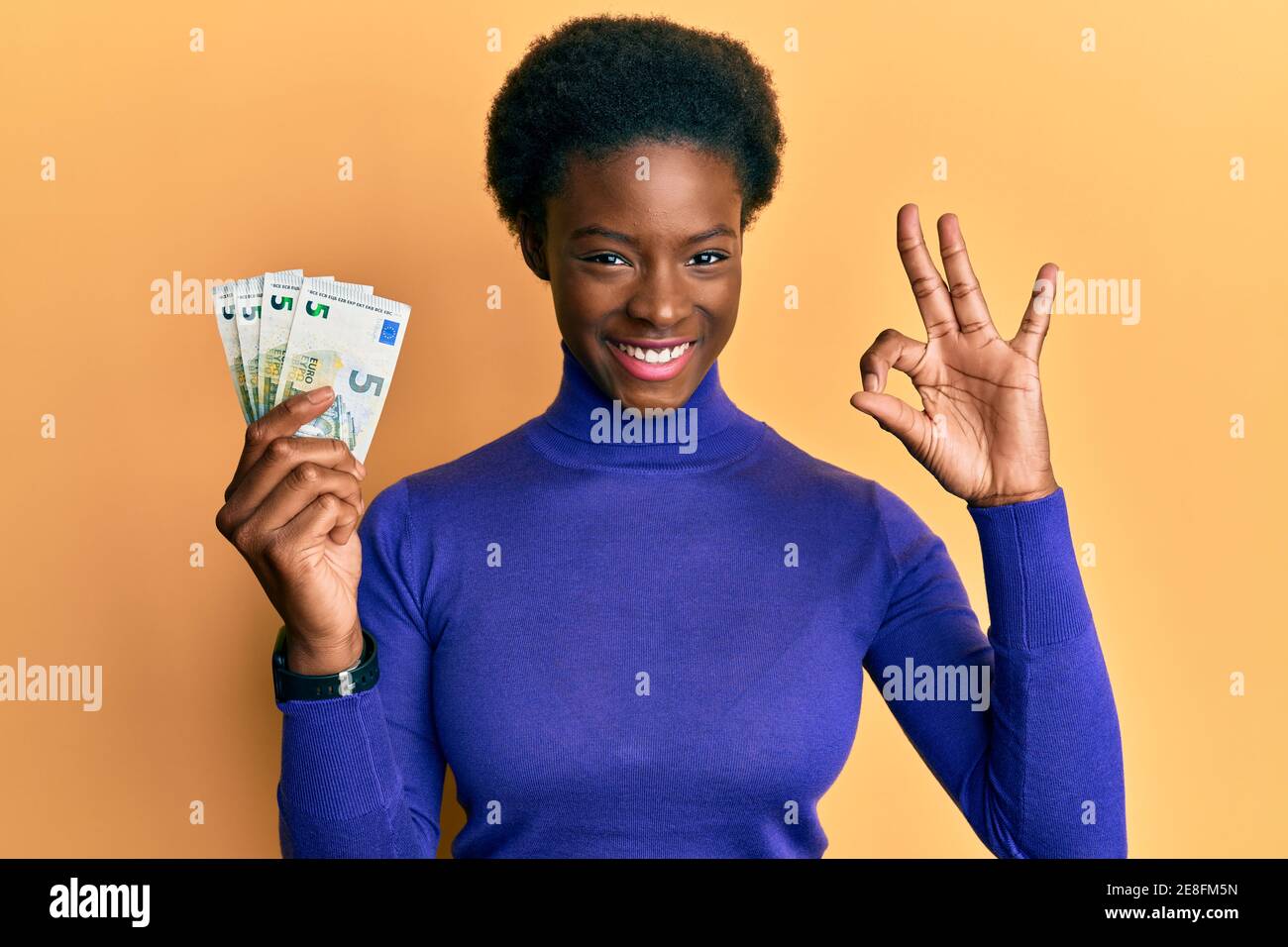Young african american girl holding bunch of 5 euro banknotes doing ok ...