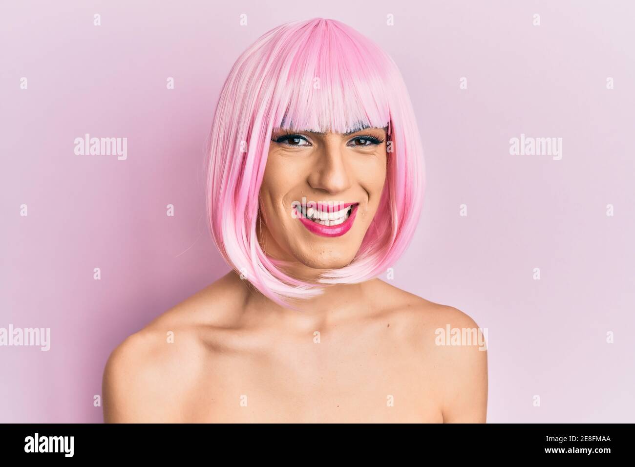 Young man wearing woman make up wearing pink wig with a happy and cool ...