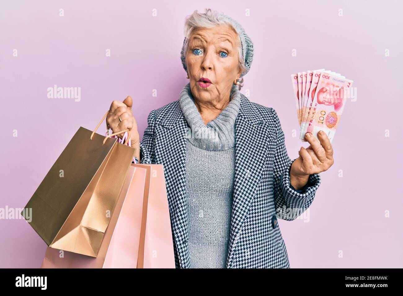 Senior grey-haired woman holding shopping bags and israel shekels ...