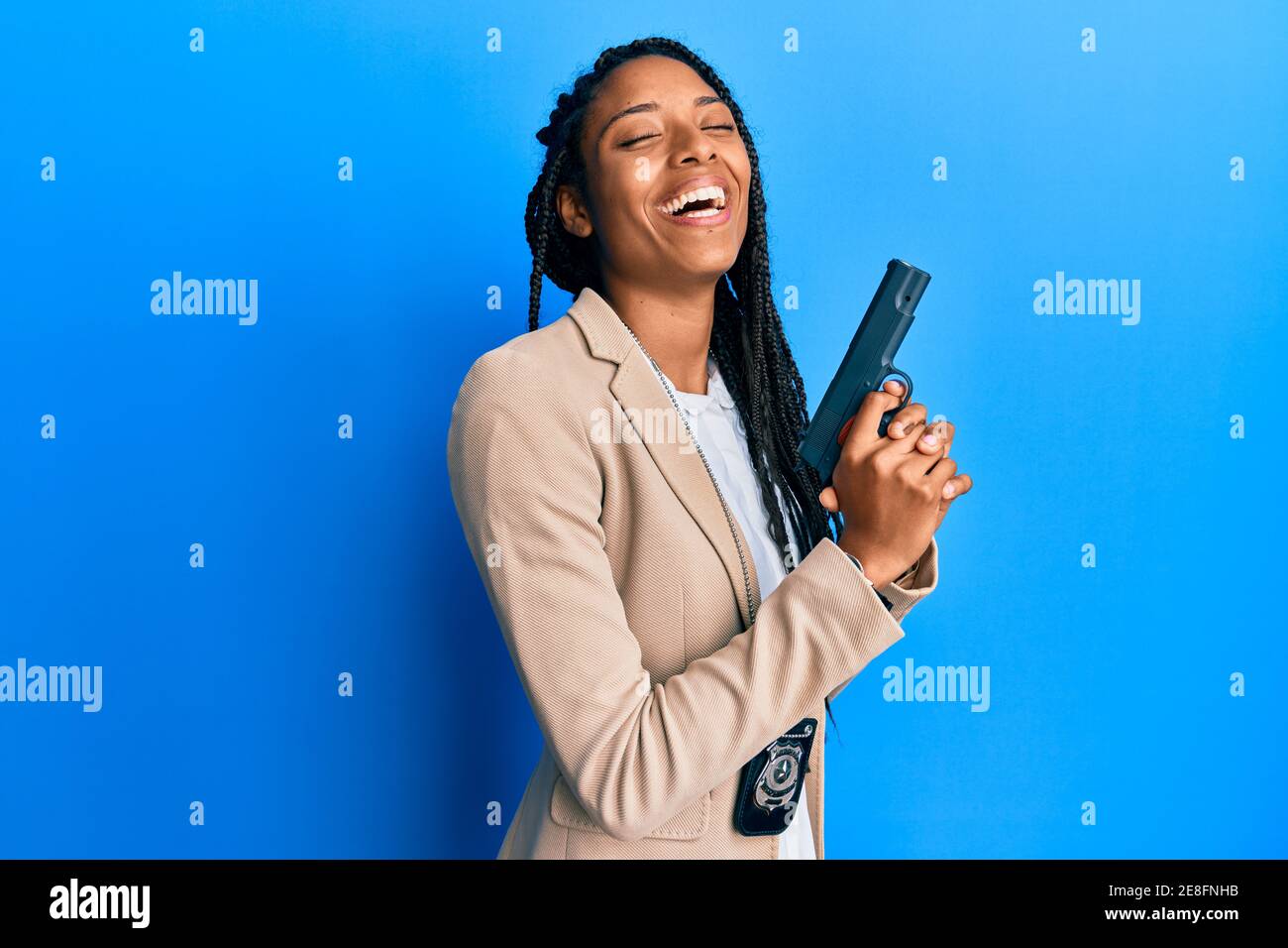 African american police woman holding gun smiling and laughing hard out ...
