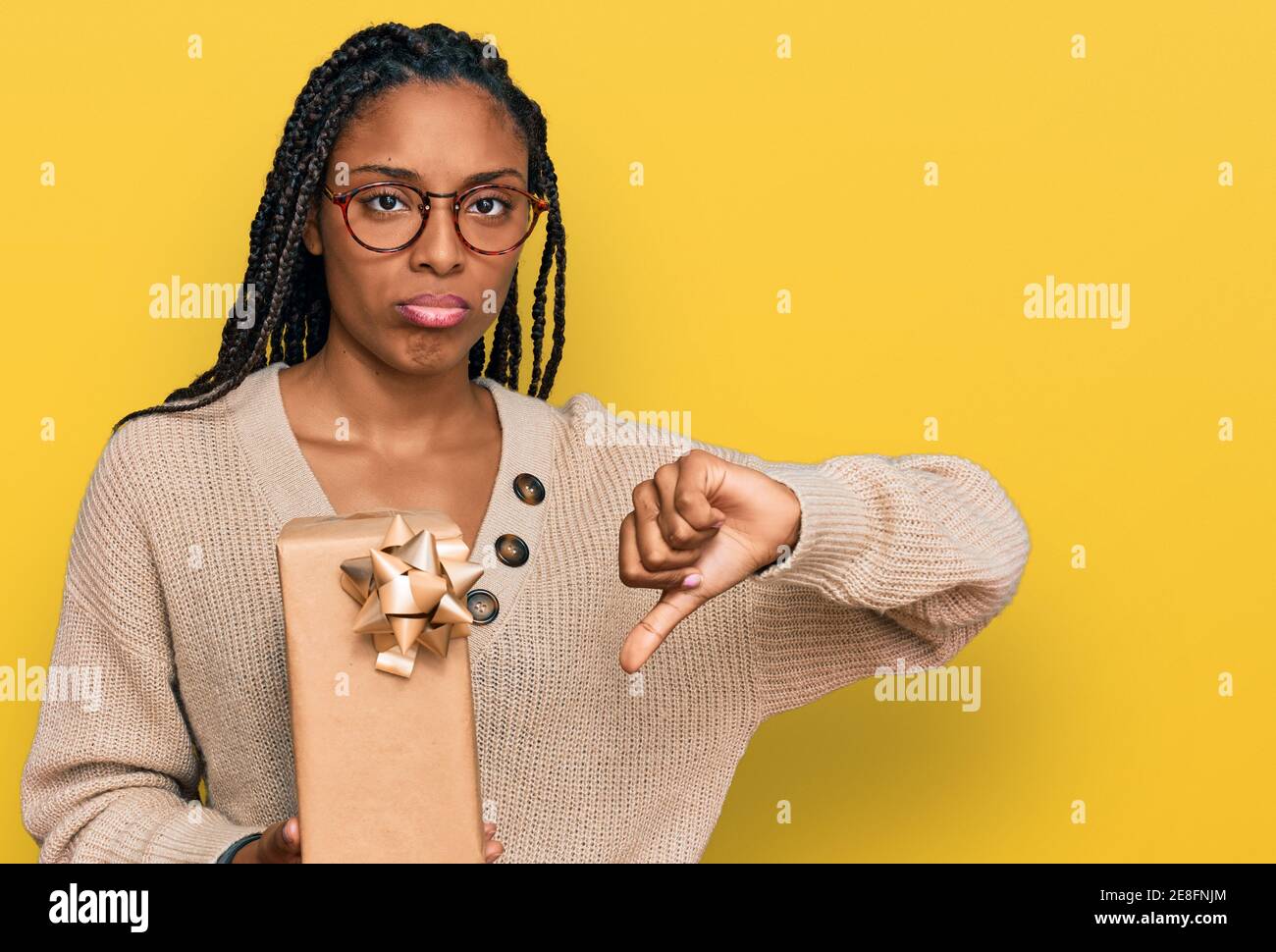 African american woman holding gift with angry face, negative sign ...