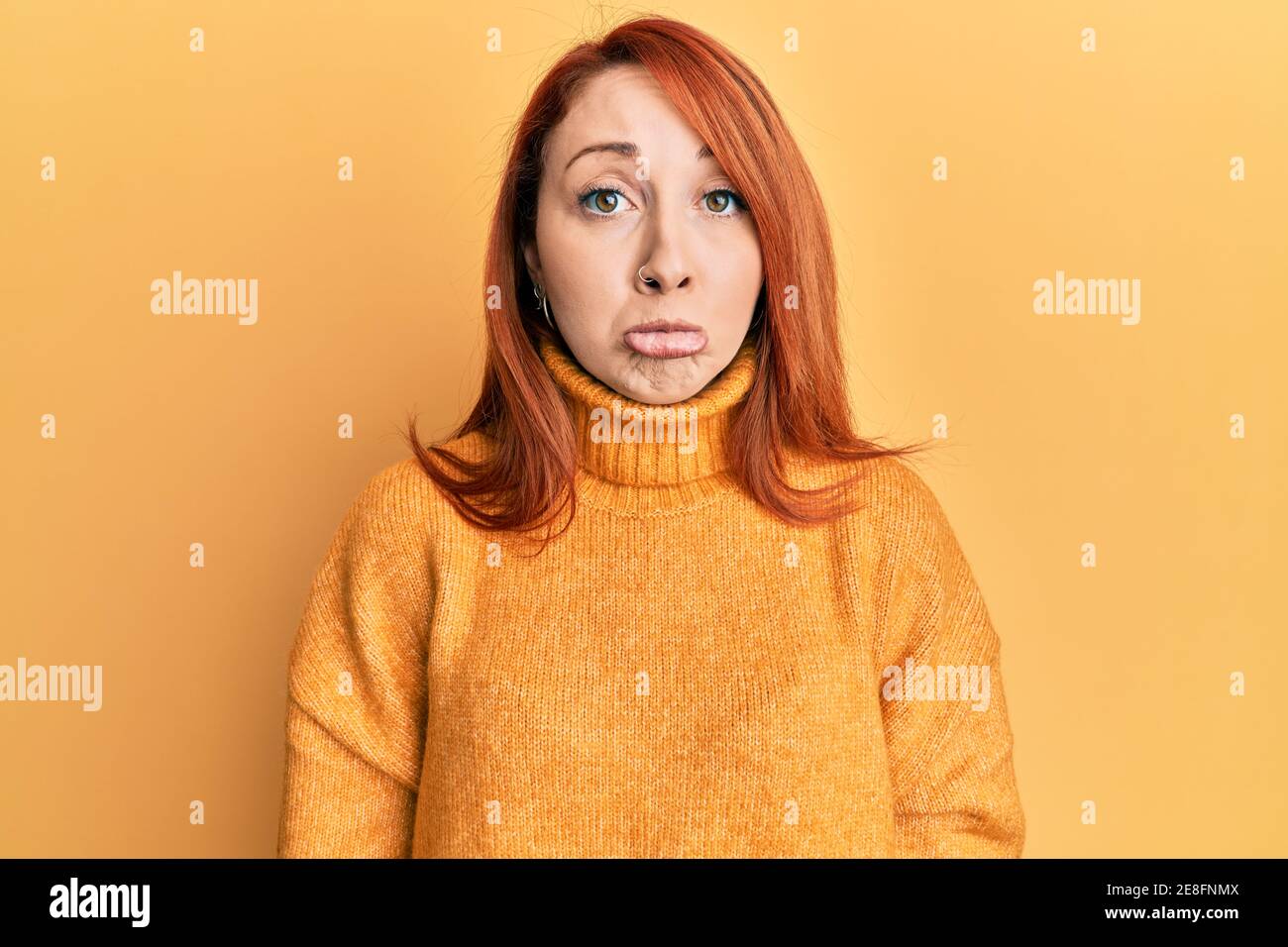Beautiful redhead woman wearing casual winter sweater over yellow ...