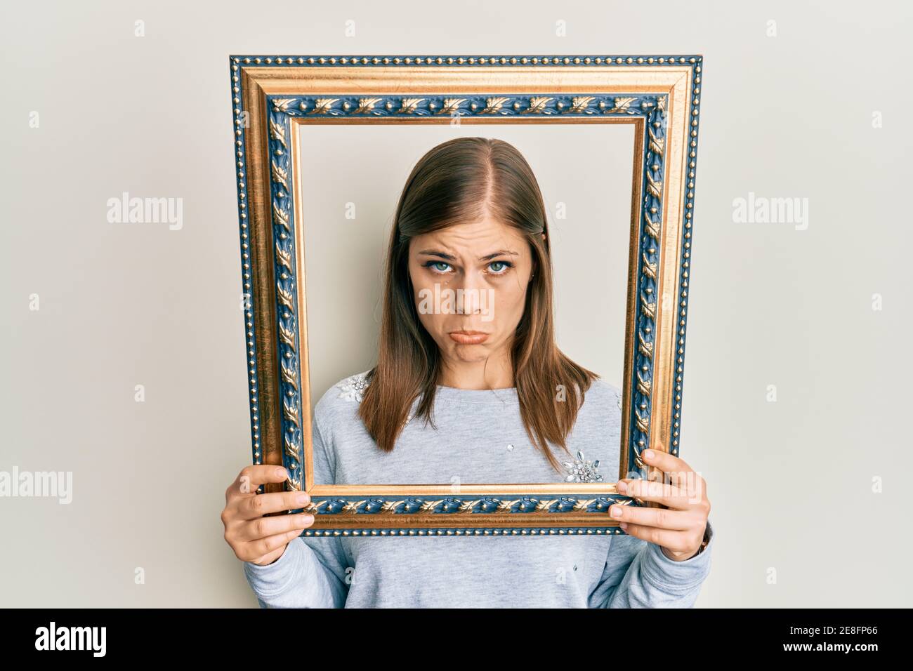 Beautiful caucasian woman holding empty frame depressed and worry for ...