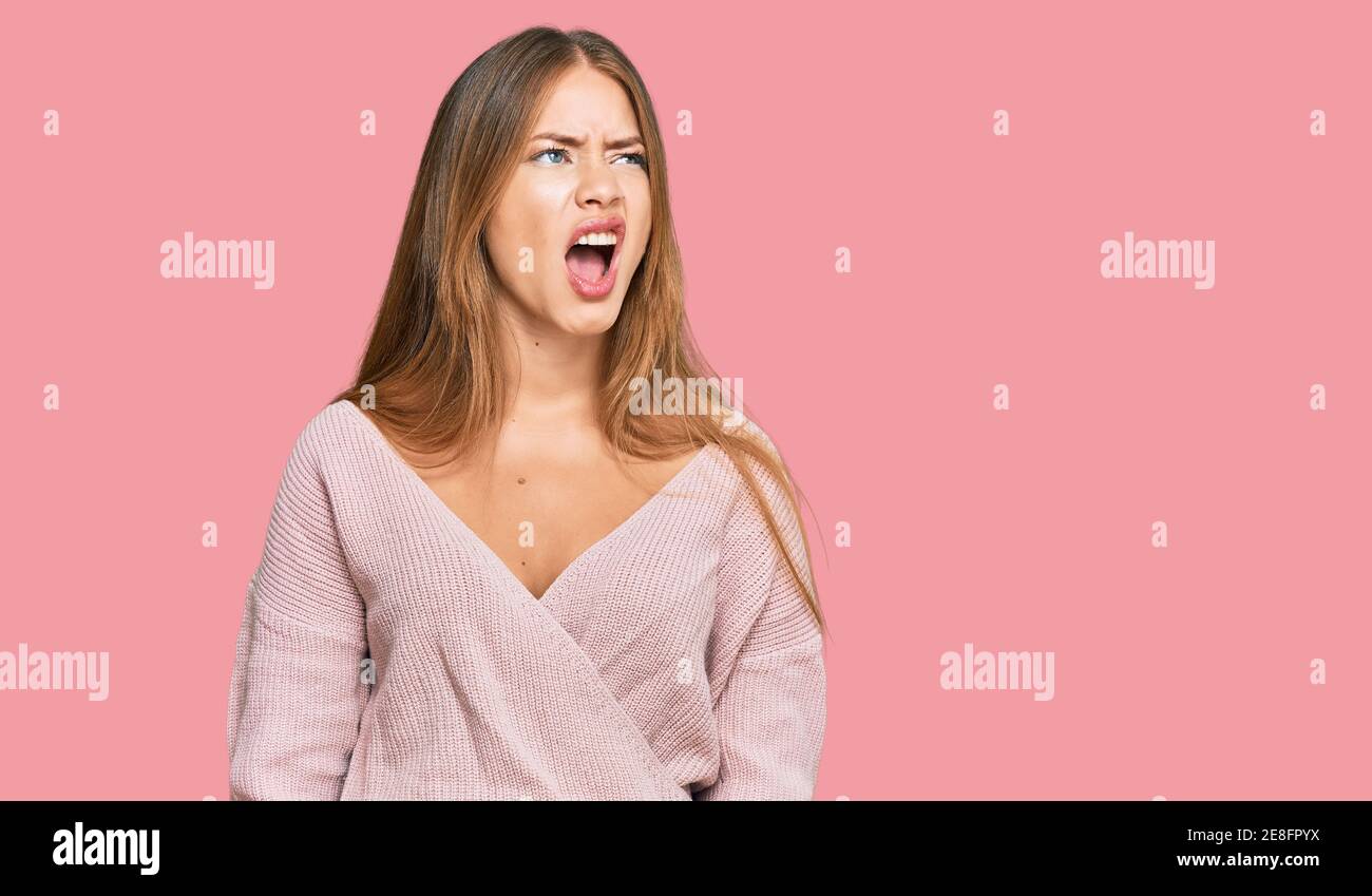 Beautiful blonde woman wearing casual winter pink sweater angry and mad ...