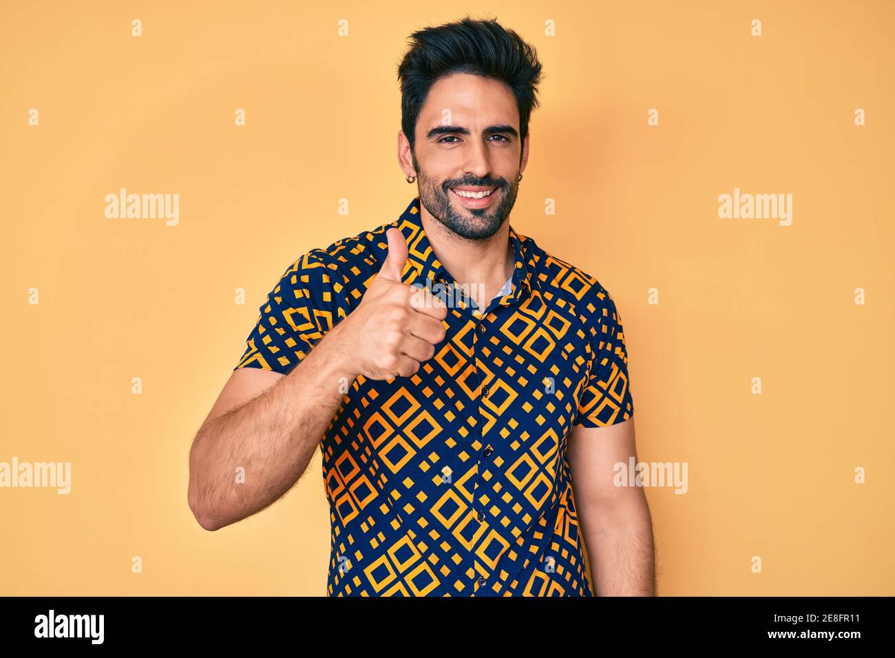 Handsome hispanic man with beard wearing 80s disco style shirt doing ...