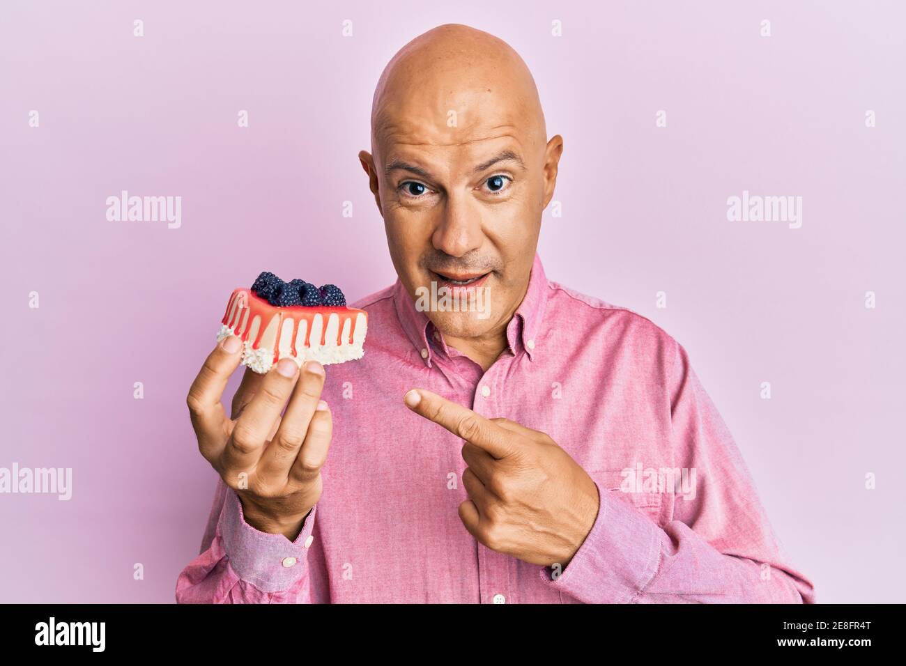 Middle age bald man holding cheesecake smiling happy pointing with hand ...