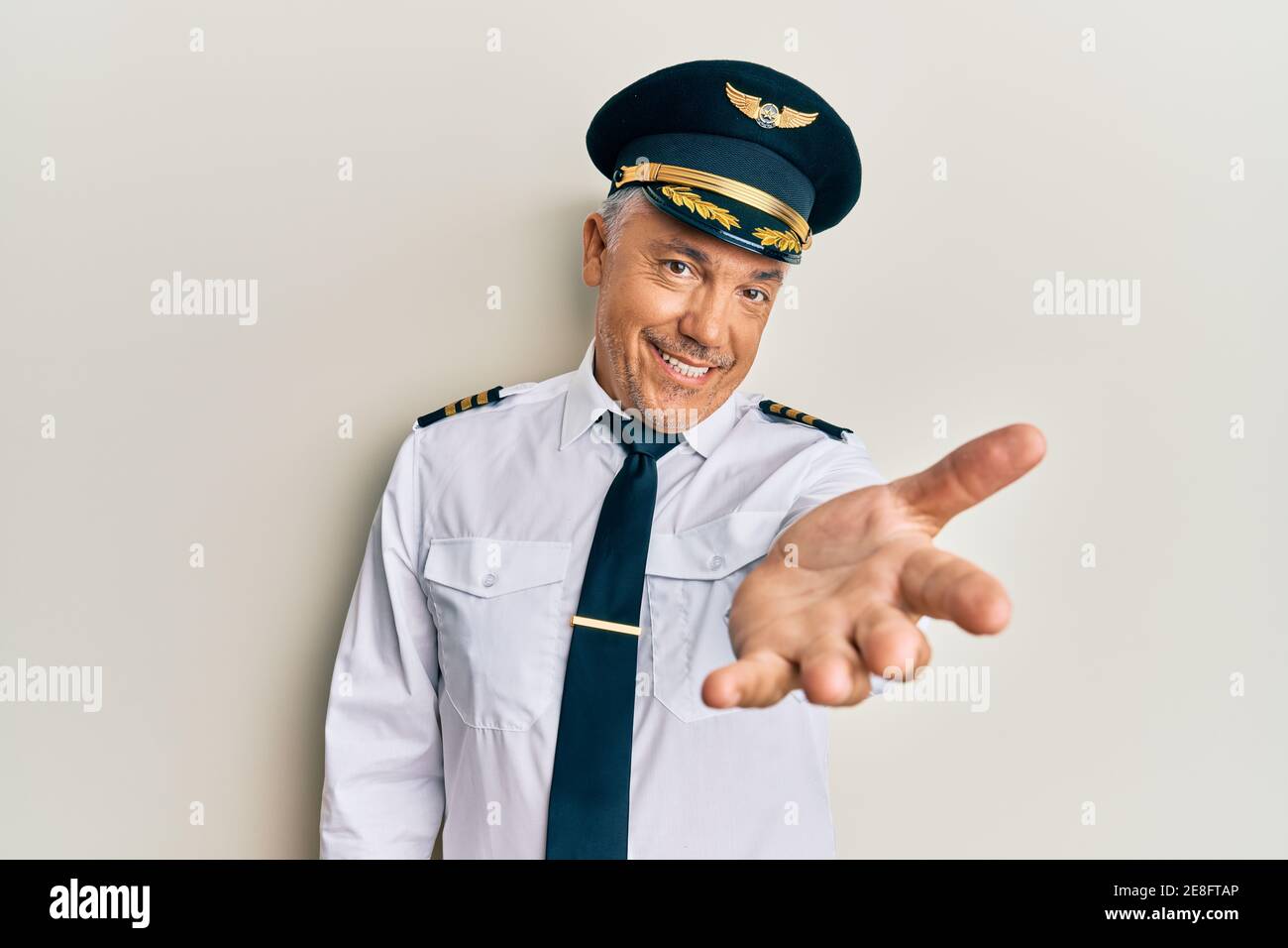 Handsome middle age mature man wearing airplane pilot uniform smiling ...