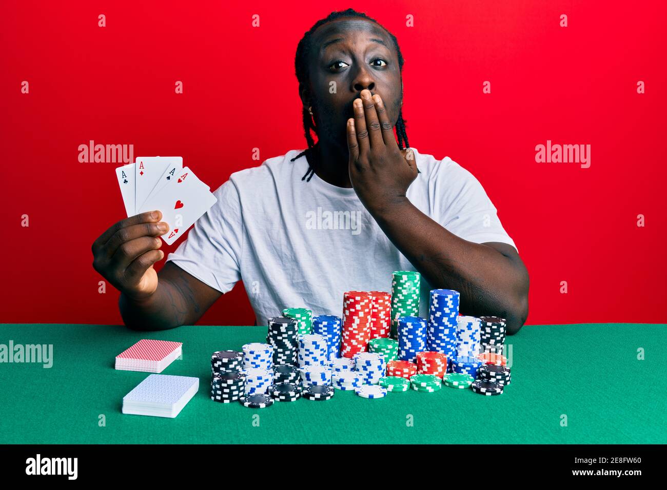 Handsome young black man playing poker holding cards covering mouth ...