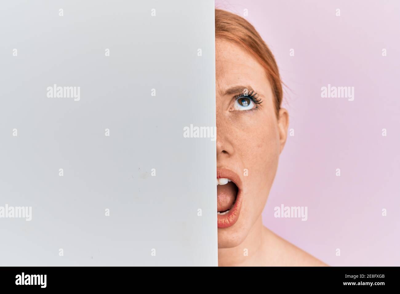 Young irish woman holding blank empty banner showing half face angry ...
