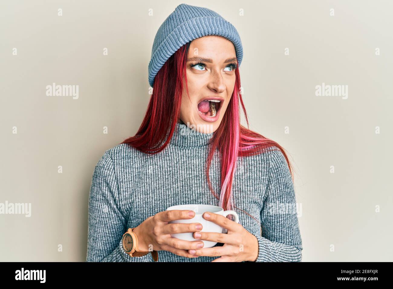 Young caucasian woman wearing winter cap and drinking a cup of hot ...