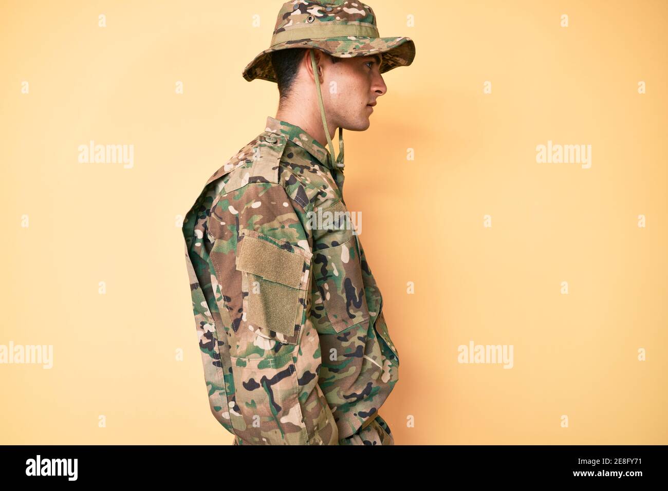 Young handsome man wearing camouflage army uniform looking to side ...