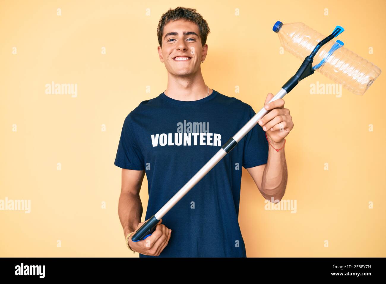 Young handsome man recycling plastic bottle holding litter pick up tool ...