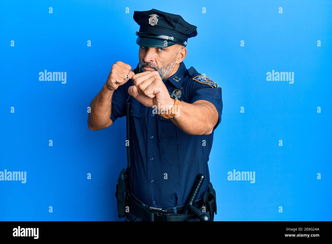 Middle age handsome man wearing police uniform punching fist to fight ...