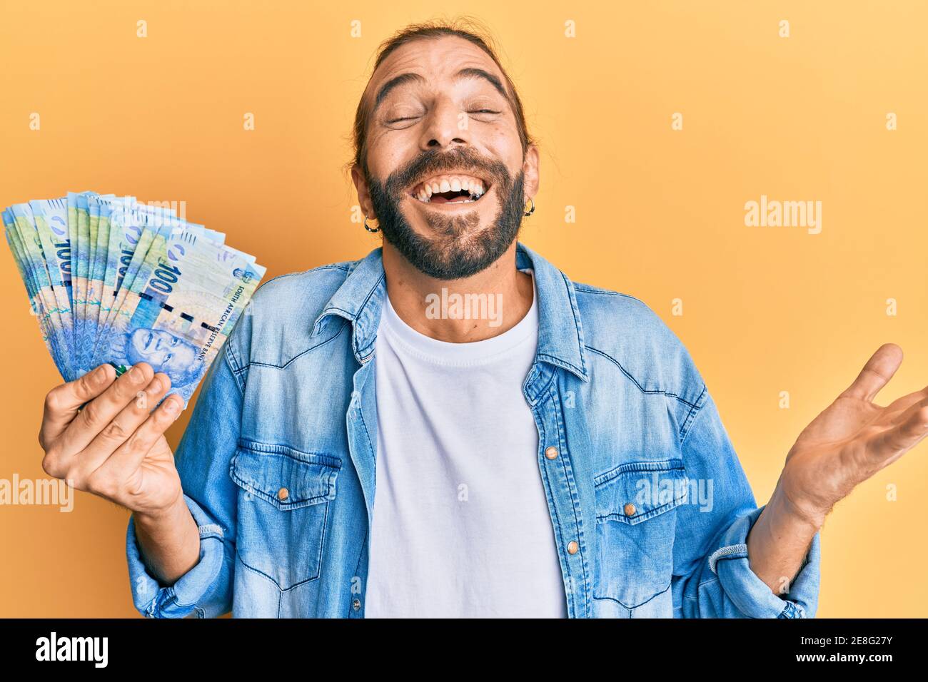 Attractive man with long hair and beard holding south african 100 rand ...