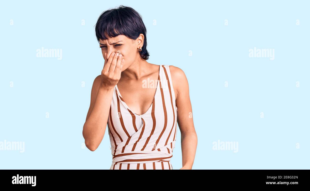 Young brunette woman with short hair wearing summer outfit smelling ...