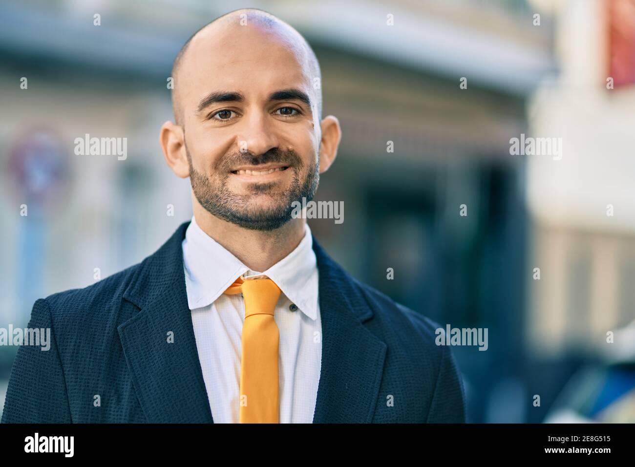 Young hispanic bald businessman smiling happy standing at the city ...