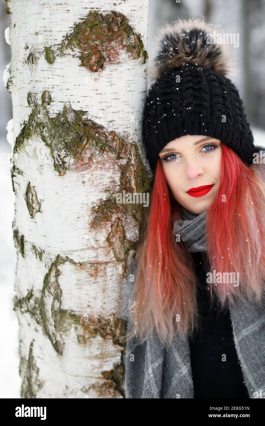 Portrait of attractive red hair girl with head resting on a birch trunk ...
