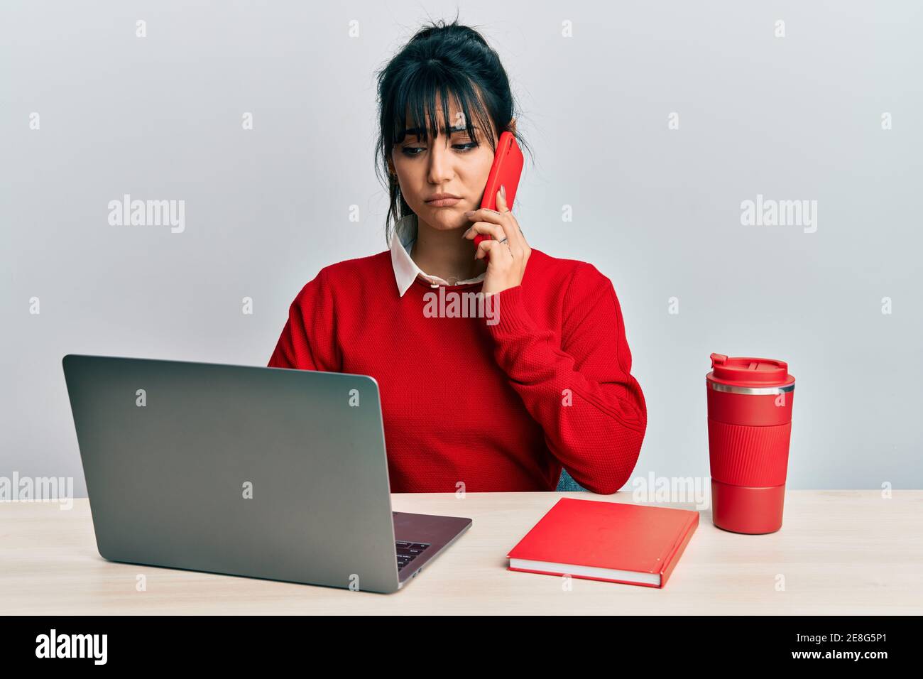 Young brunette woman with bangs working at the office talking on the ...