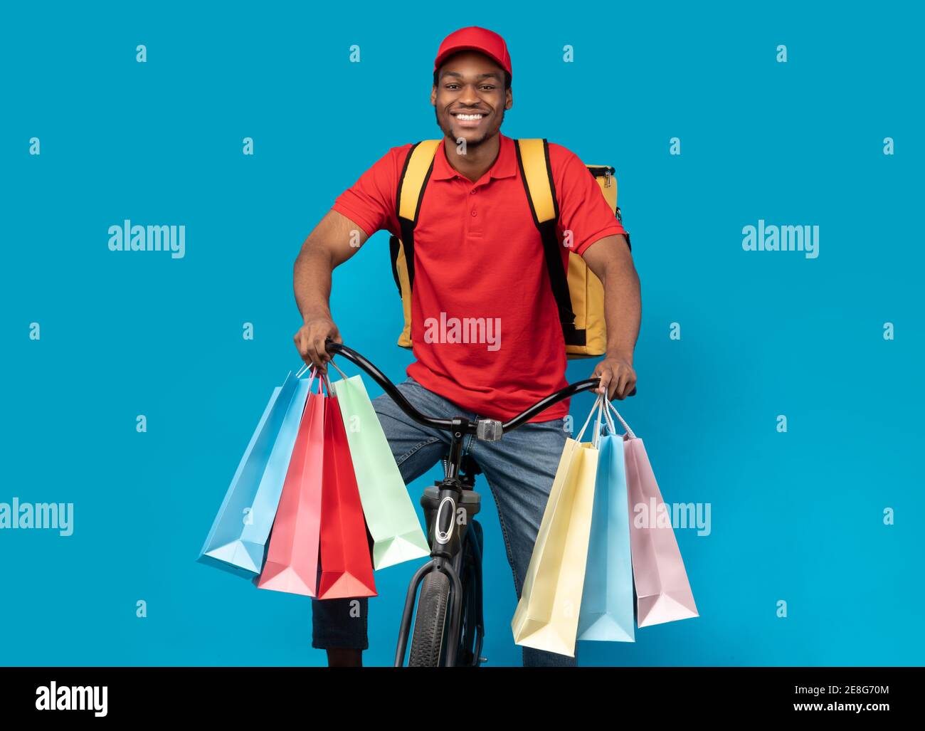 Smiling black delivery man riding bicycle with shopping bags Stock ...