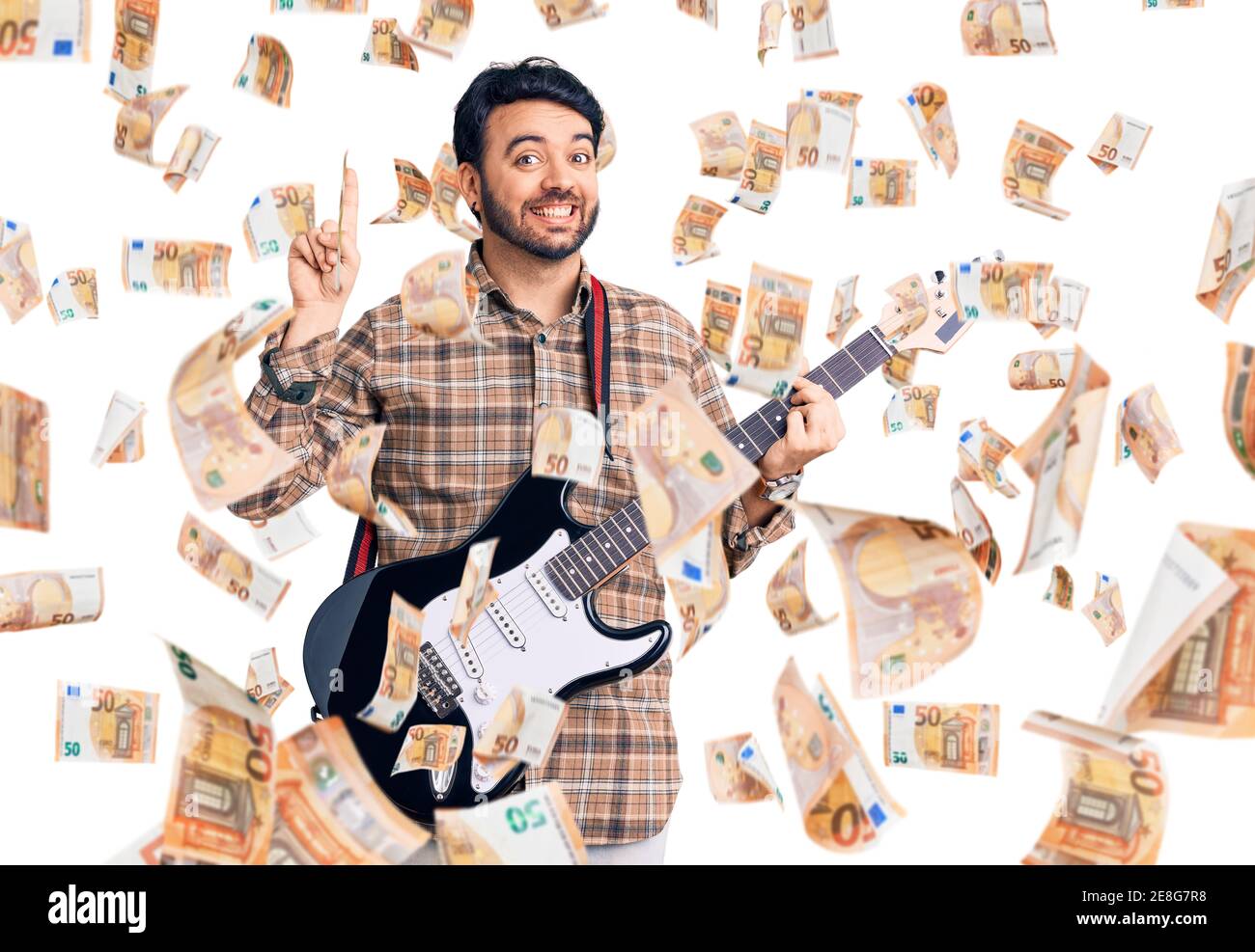 Young hispanic man playing electric guitar surprised with an idea or ...