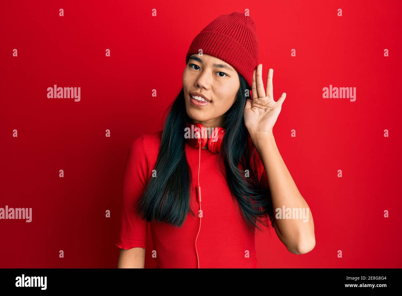 Young chinese woman listening to music using headphones smiling with ...