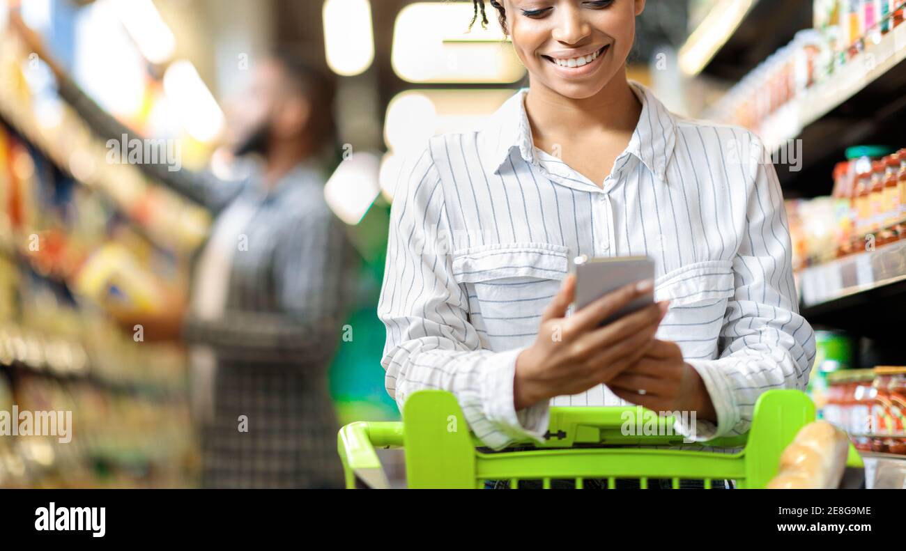 African Woman Using Grocery Shopping App On Smartphone In Supermarket ...