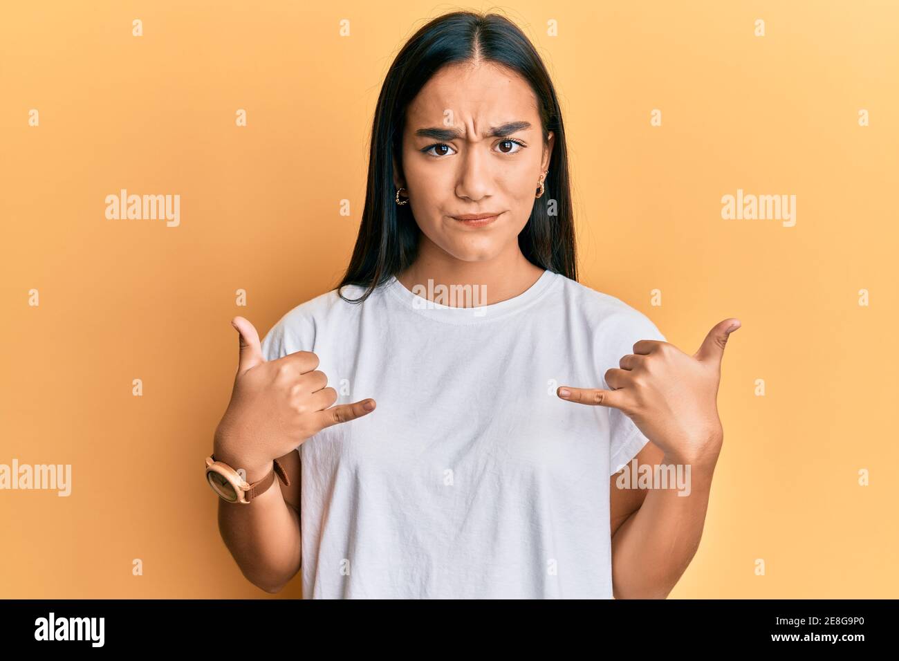 Young asian woman doing shaka sign with hands skeptic and nervous ...