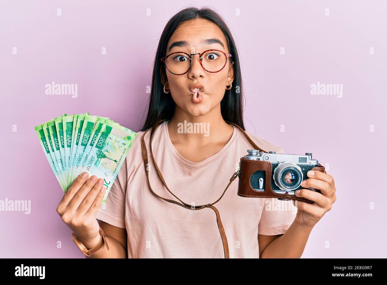 Young asian woman holding vintage camera and 200 russian ruble ...