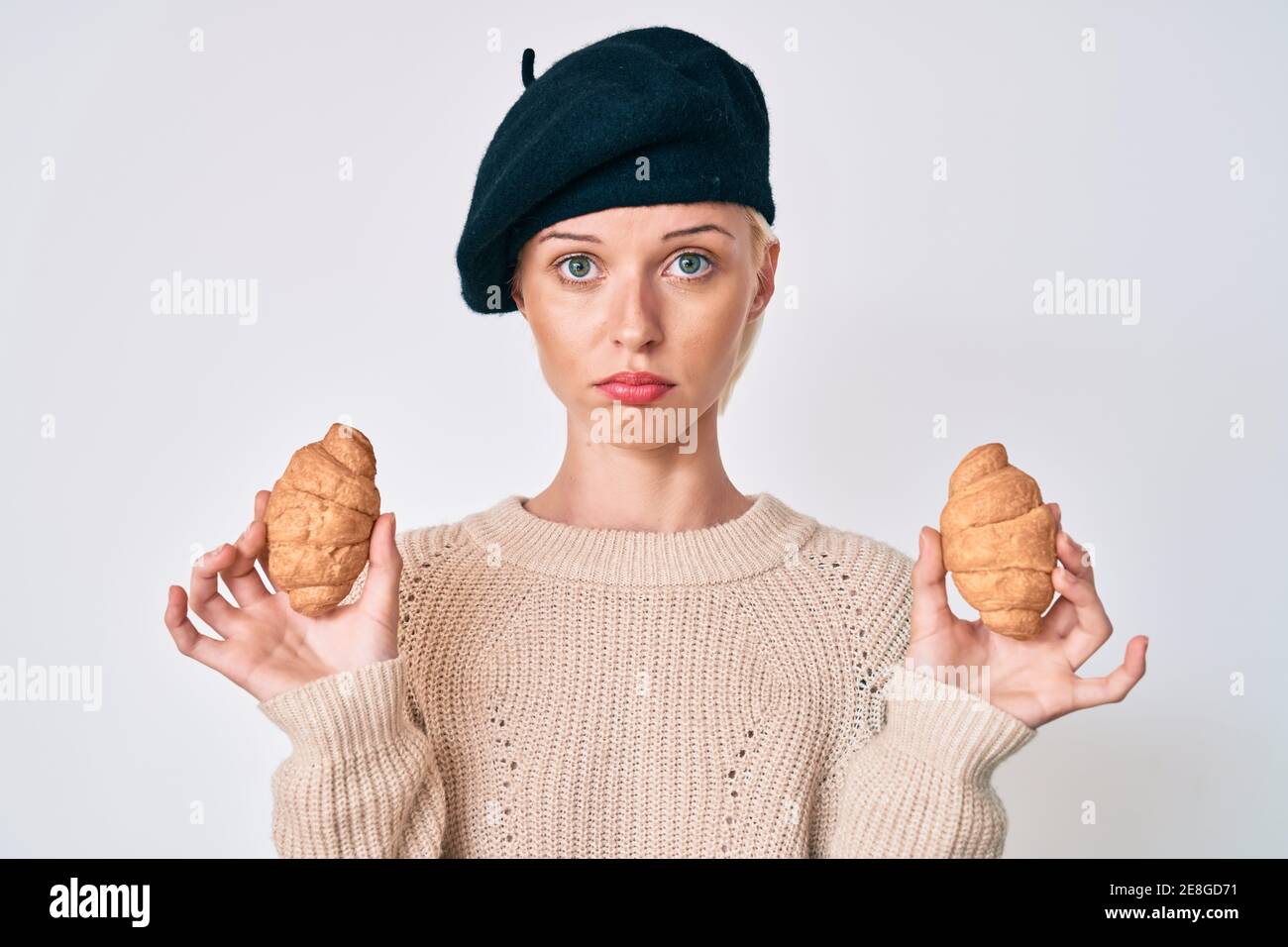 Young caucasian woman wearing french look with beret holding croissants ...