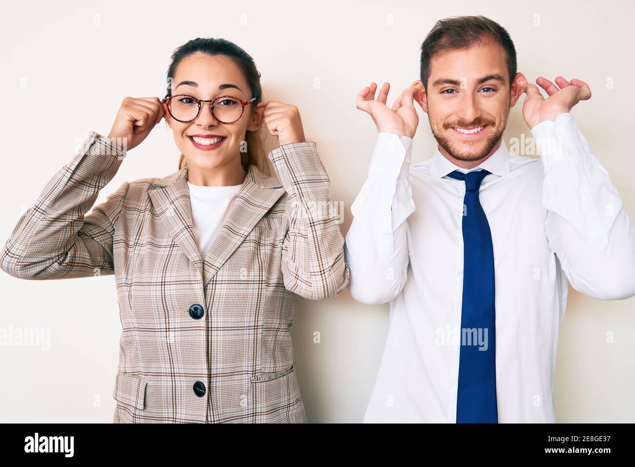 Beautiful couple wearing business clothes smiling pulling ears with ...